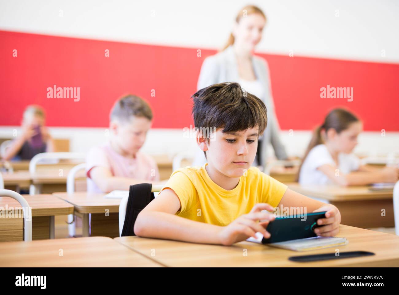 Focused tween schoolboy using mobile phone at lesson in class Stock ...