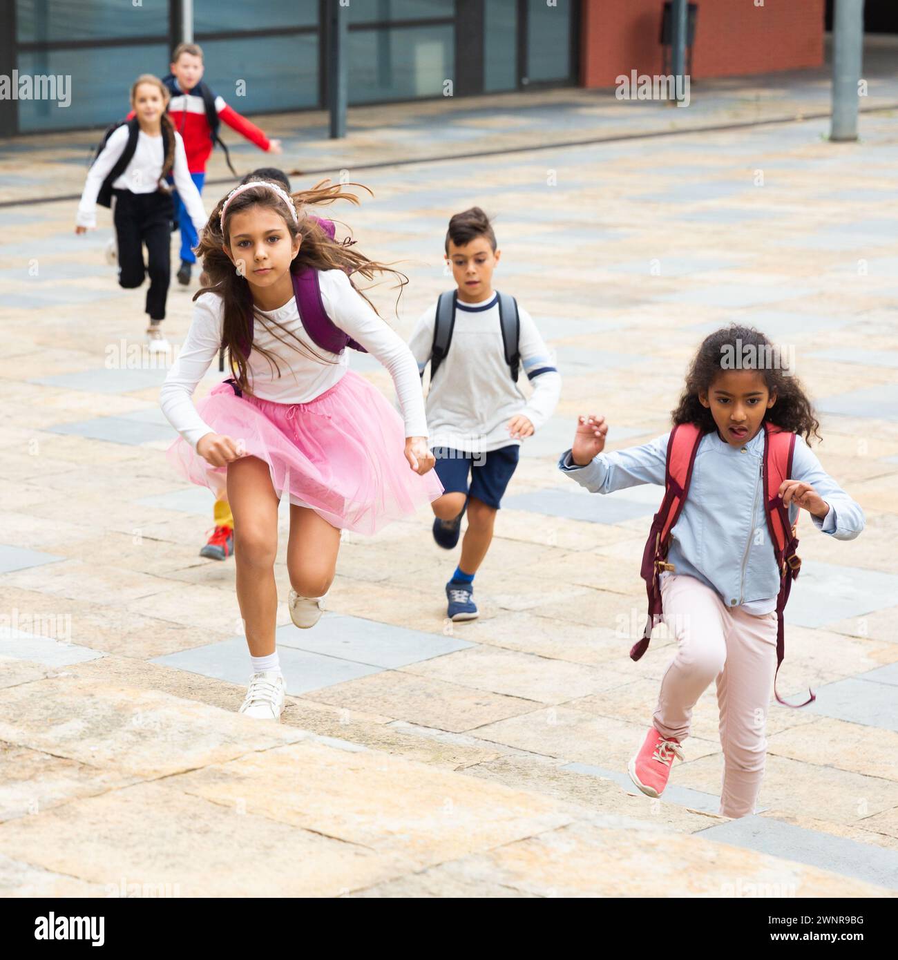 Tween boys and girls with school backpacks running in schoolyard Stock ...