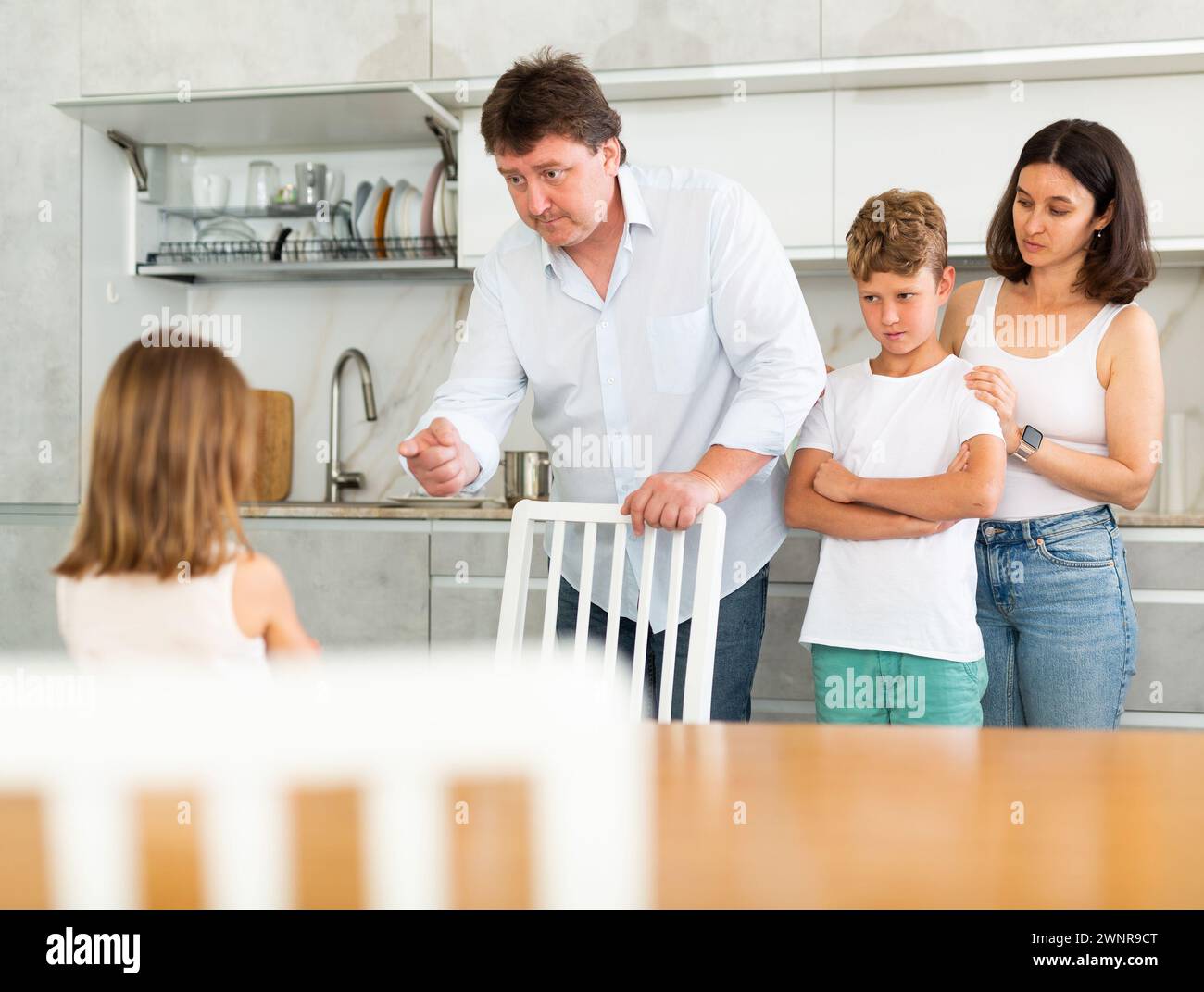 At home in kitchen, parents scold their daughter for careless act Stock ...