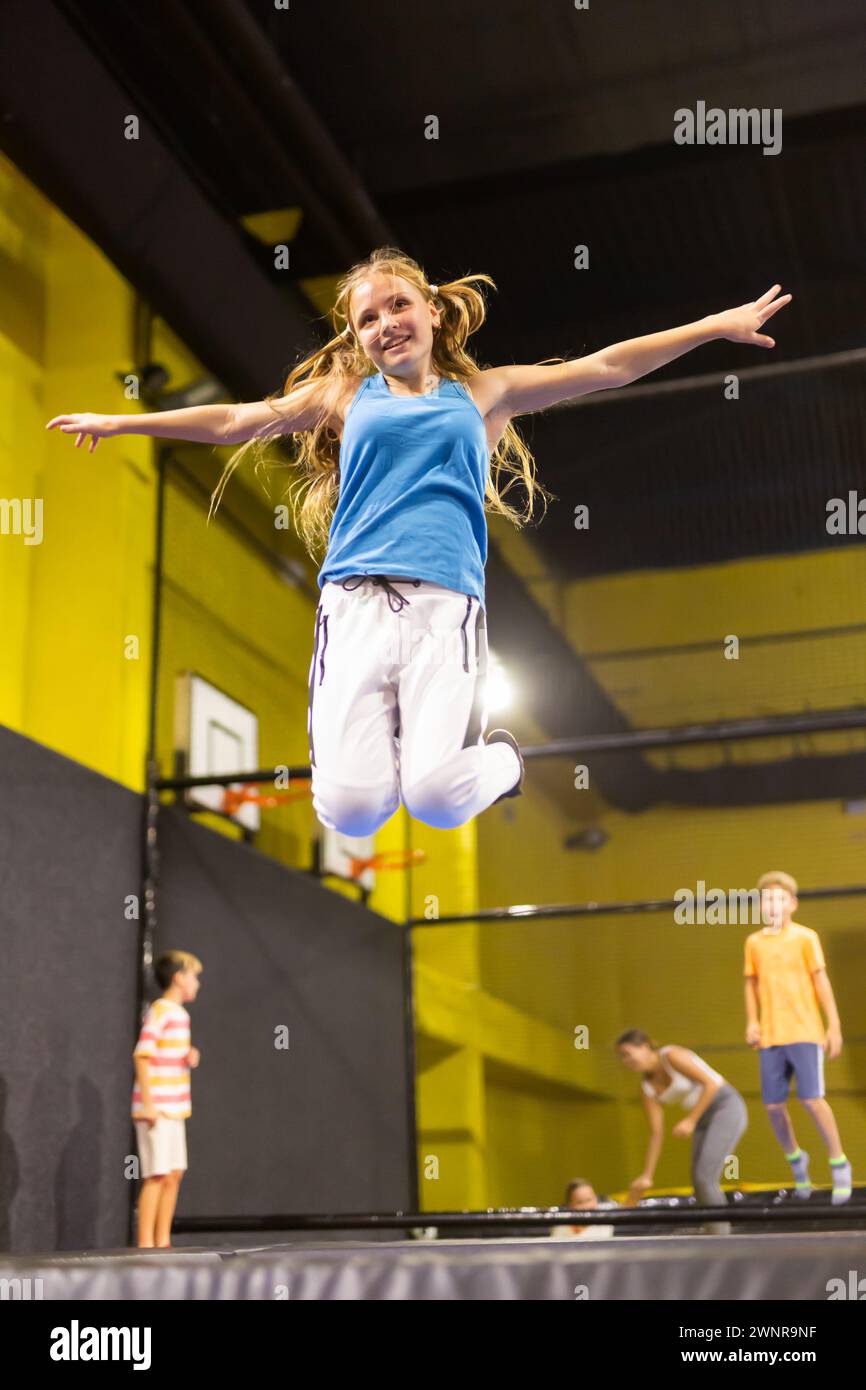 Happy teen girl in blue jersey and white pants jumping and indulging on ...
