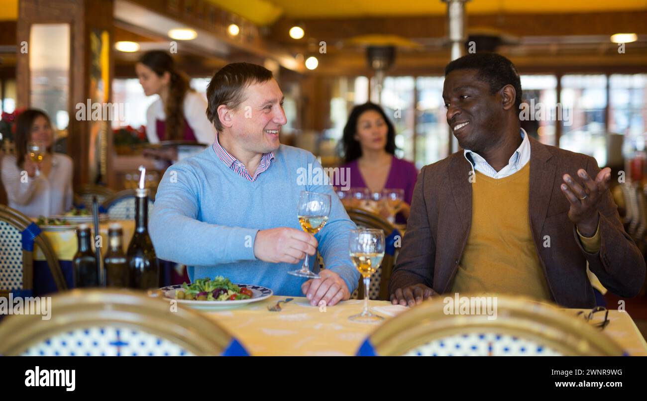 Two men drinking wine and talking in restaurant Stock Photo - Alamy