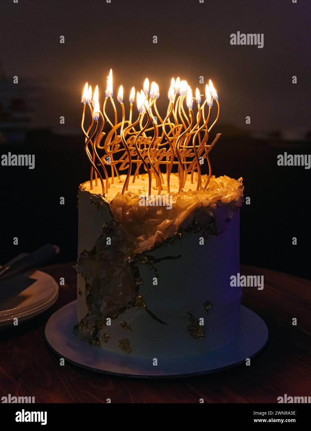A beautifully decorated birthday cake with tall lit candles providing a ...