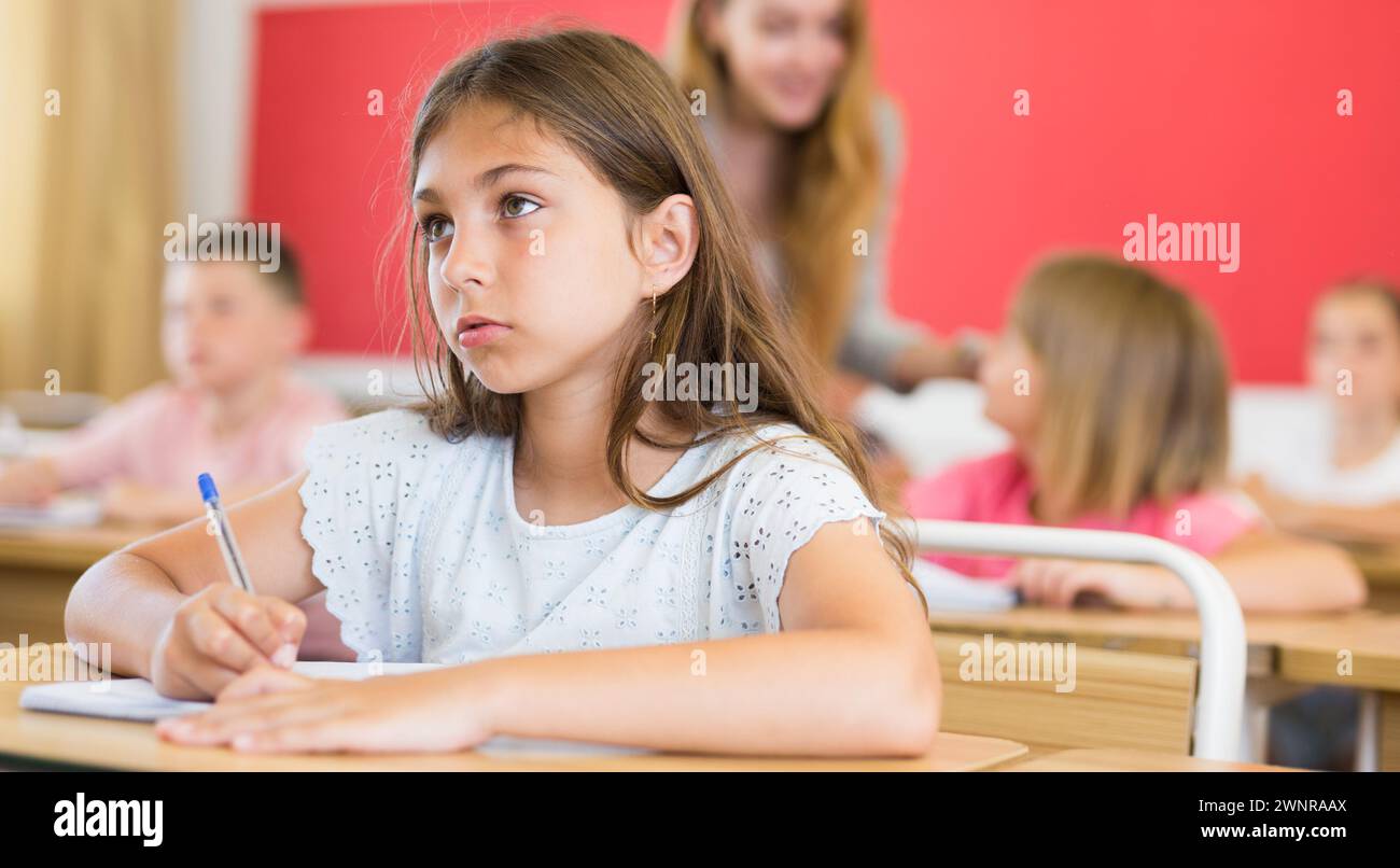 Schoolgirl sitting in classroom during lesson in elementary school ...