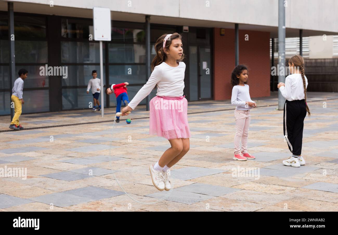 Schoolgirl jumping game by rubber band, kids friends on background ...