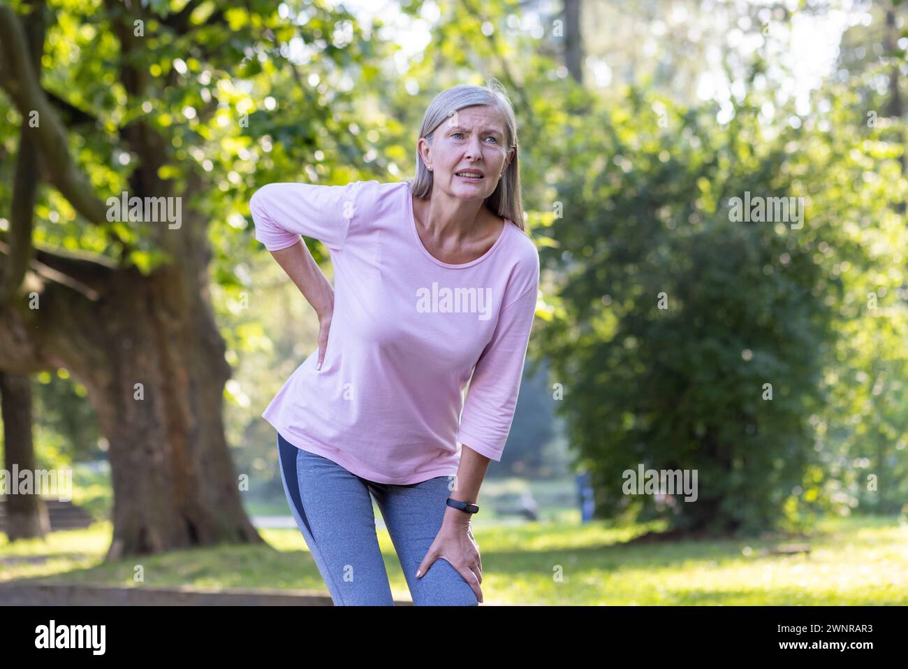 An elderly gray-haired woman felt severe back pain while walking and ...