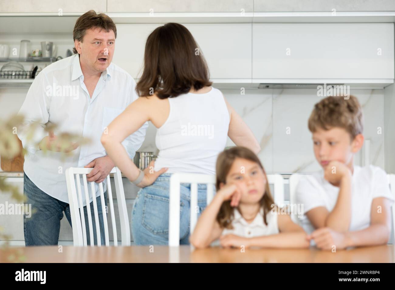 Brother and sister sit at table during quarrel between parents Stock ...