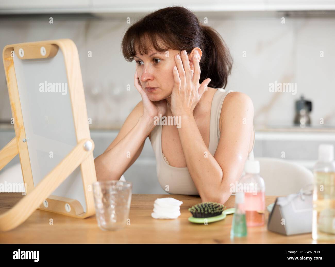 Woman examining facial skin in mirror during morning routine Stock ...