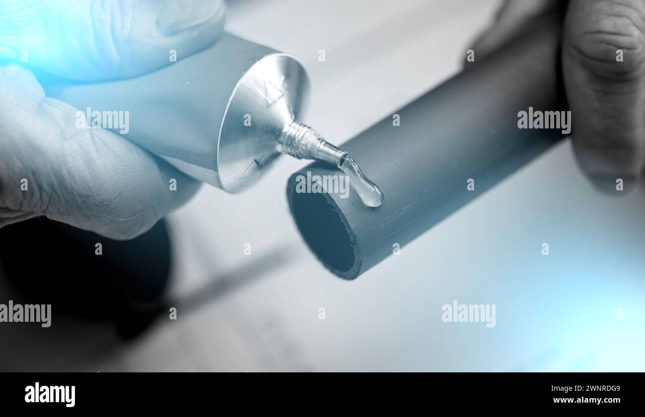 Plumber putting glue on a pvc pipe; light effect Stock Photo - Alamy