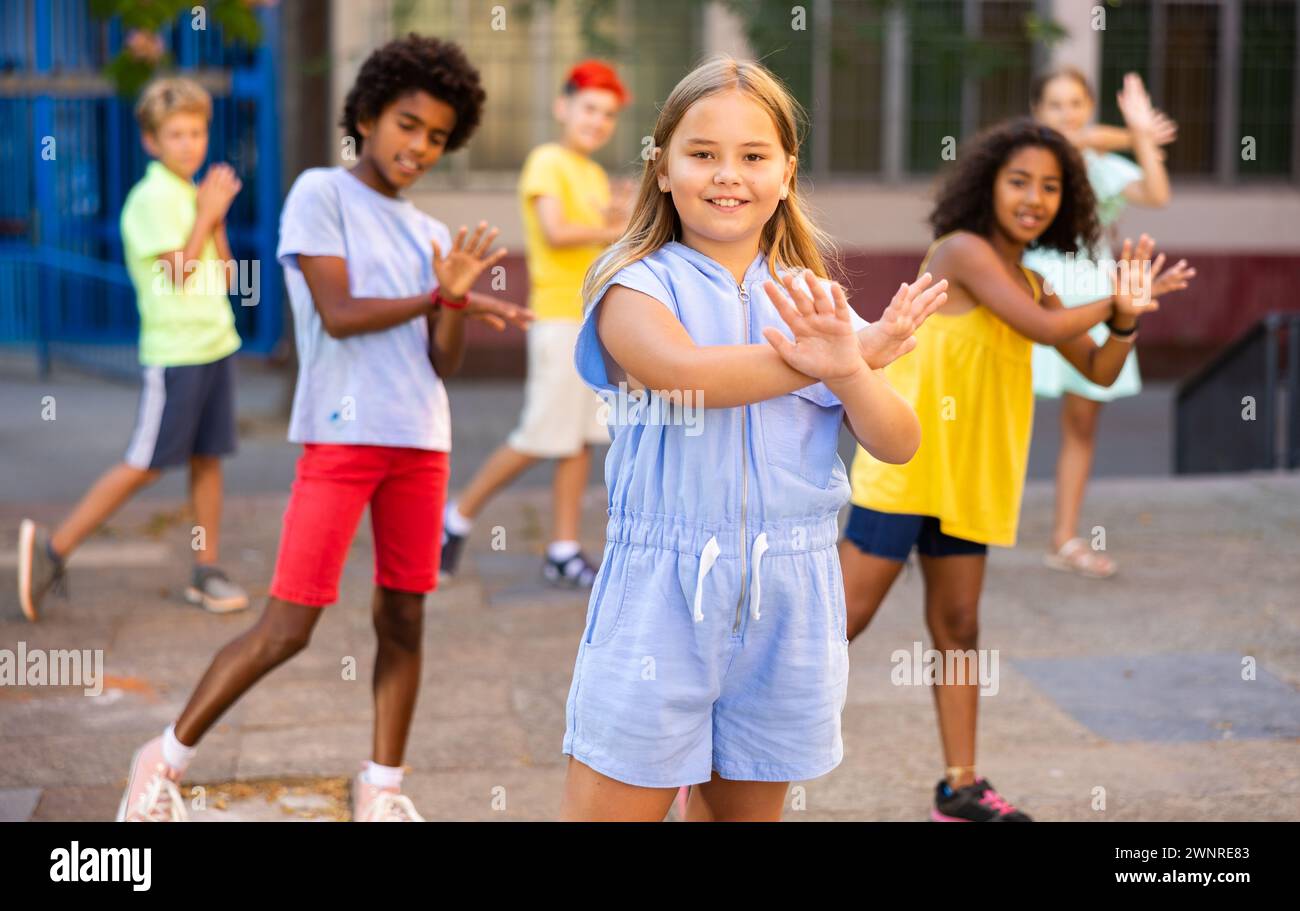 Smiling preteen girl dancing with friends on summer city street Stock ...