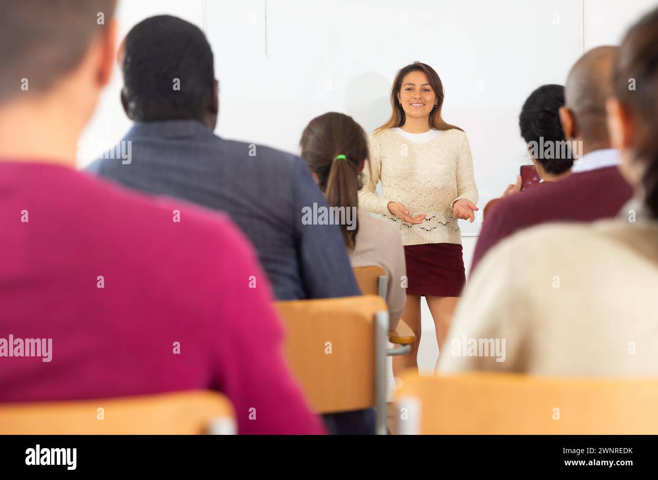 Latina teacher standing in front Of whiteboard and teaching lesson ...