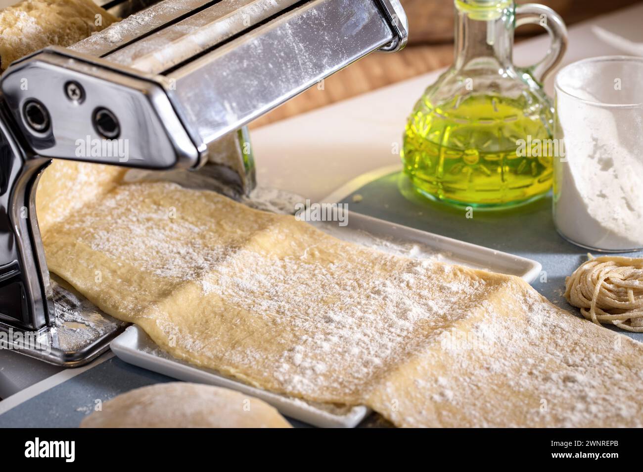 Fresh stretched dough and small home dough sheeter on kitchen Stock ...