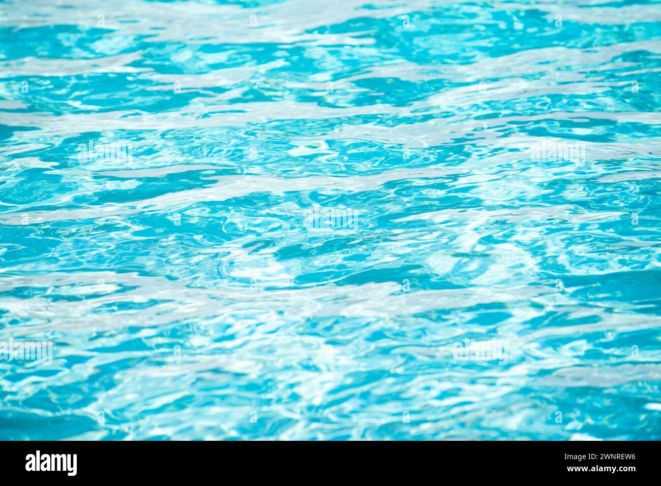 Background of blue water in swimming pool with sun reflection, ripple water wave in pool. Clear ...