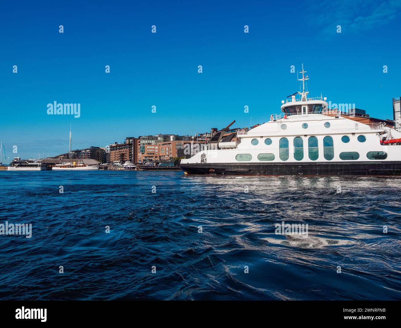 Modern ferry cruising in Oslo fjord and arriving to a city quayside ...