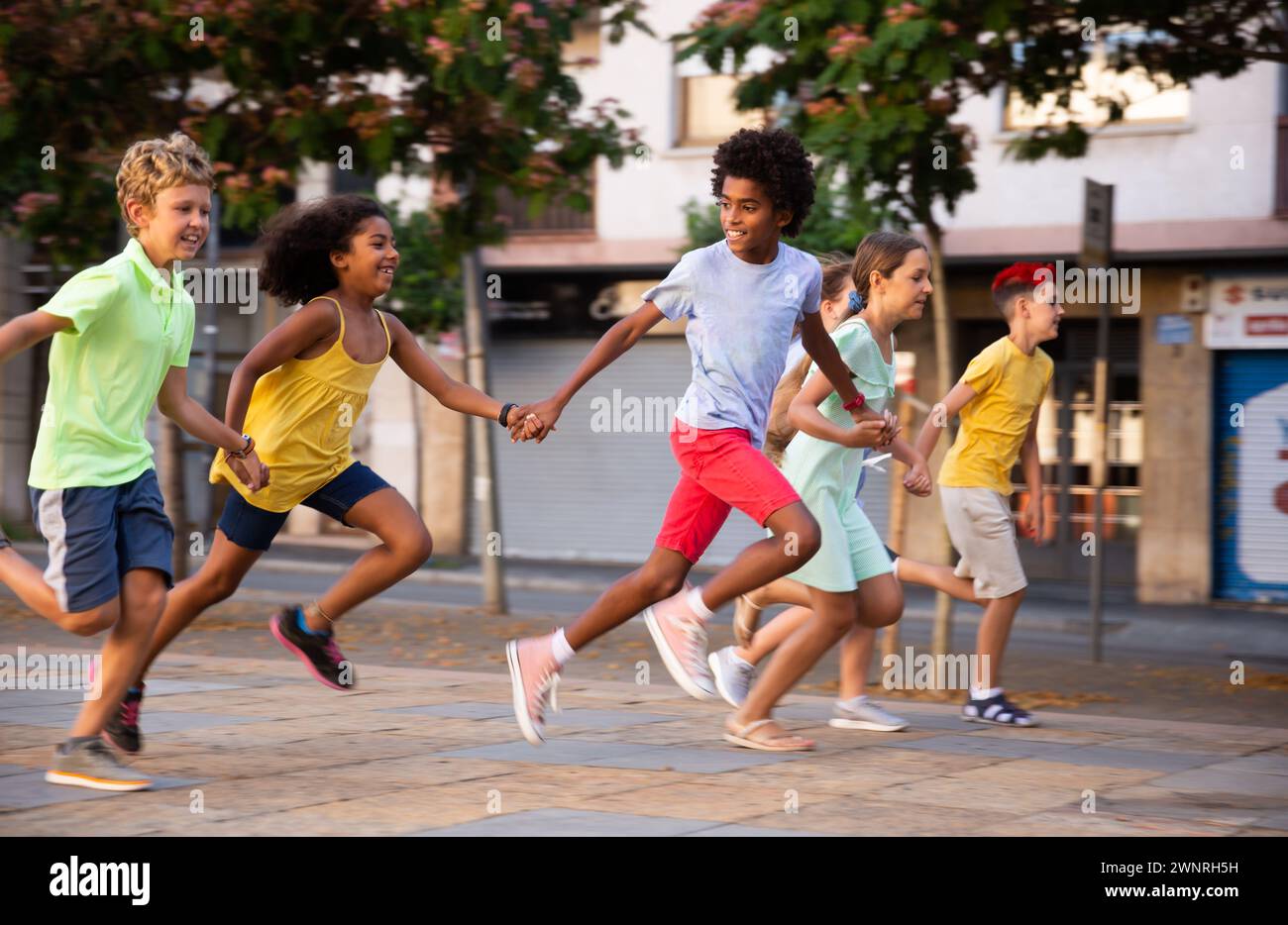 Happy children running together hand in hand through streets Stock ...