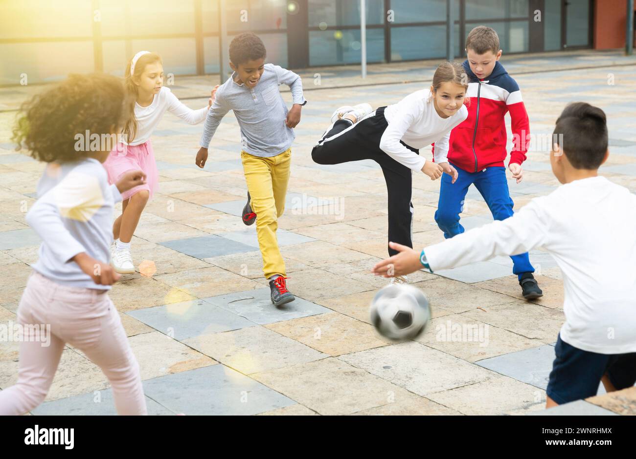 Cheerful tween schoolchildren playing with ball near school Stock Photo ...