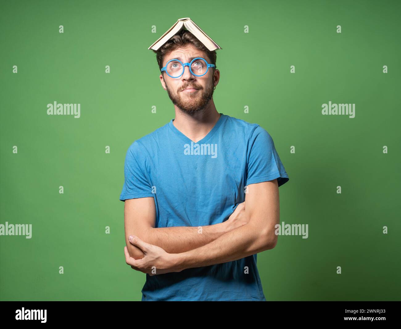 Nerdy man with quirky expression balancing book on head - Concept of ...