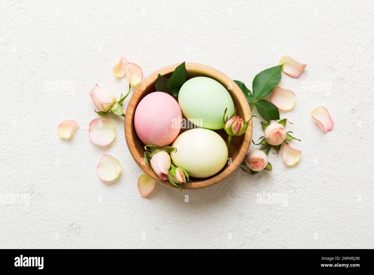 Happy Easter. Easter eggs in basket on colored table with yellow roses ...