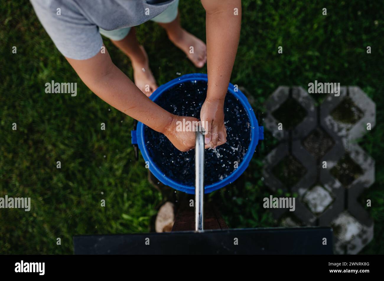 Boy washing his hands with water from a well. Well with a pump for ...