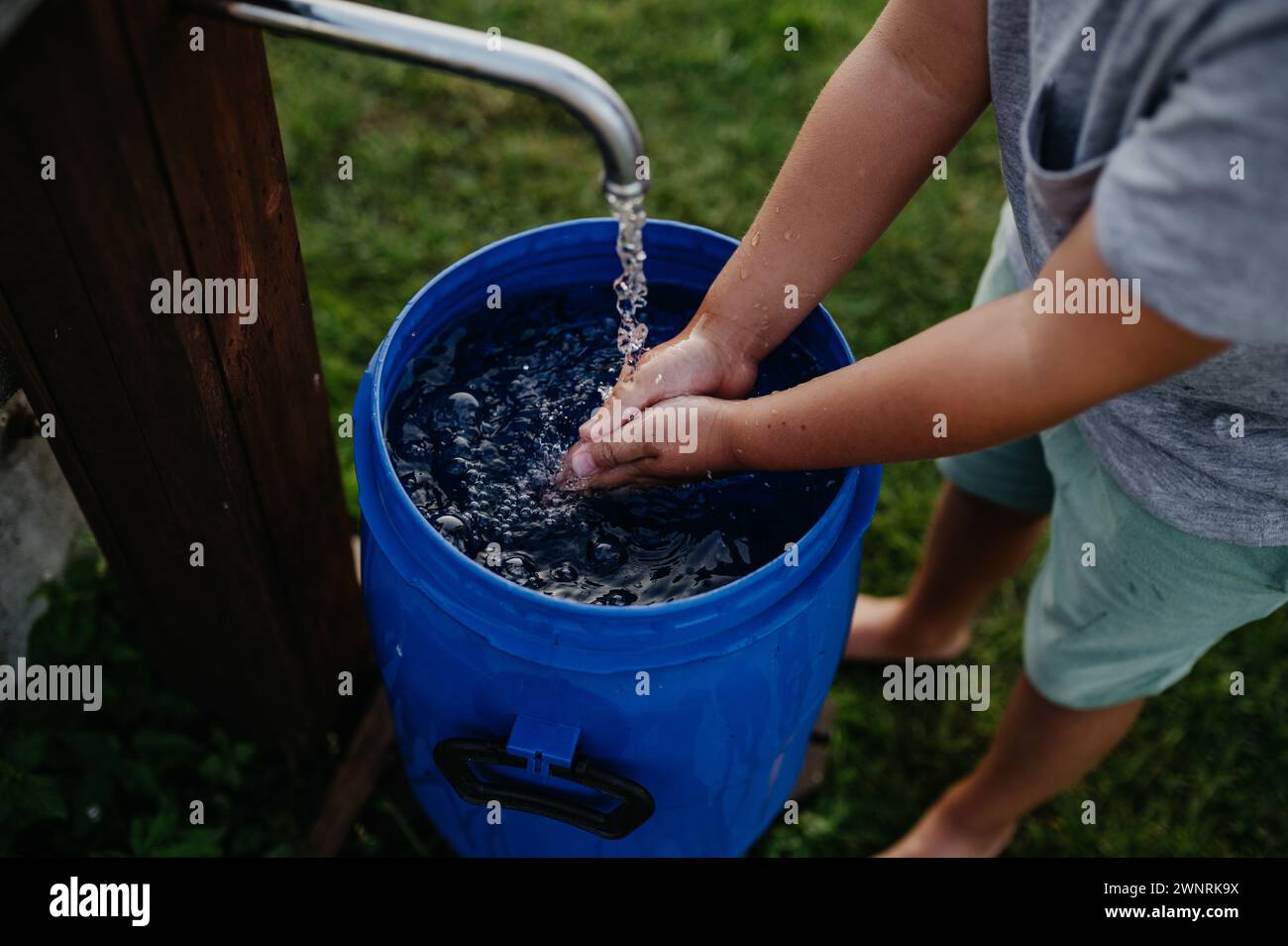 Boy washing his hands with water from a well. Well with a pump for ...