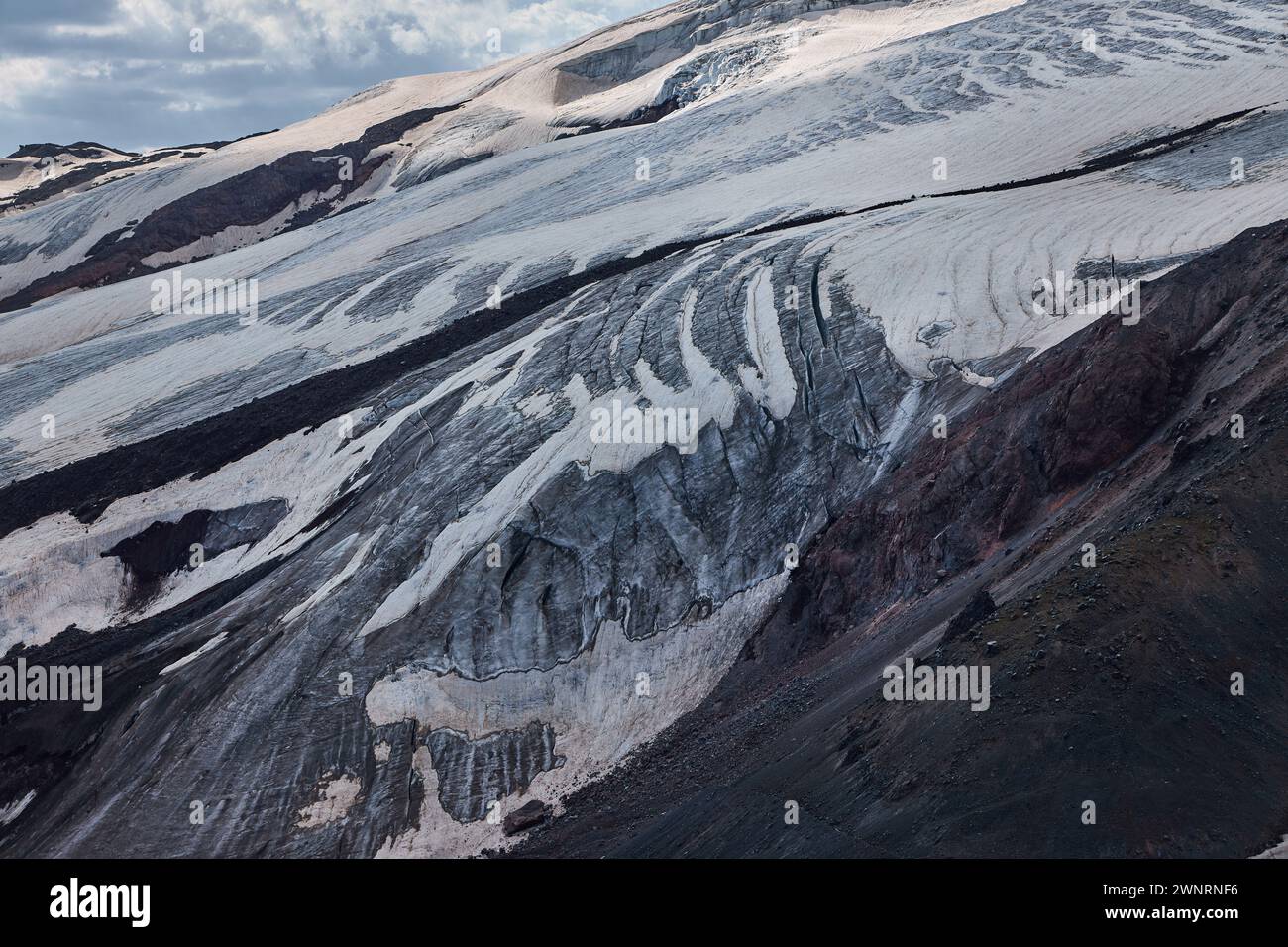Striking contrast of dark volcanic ash layers and white snow on a ...