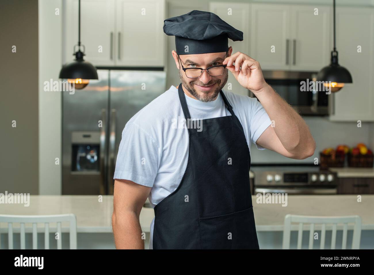 Handsome man chef in uniform cooking in the kitchen. Restaurant menu ...