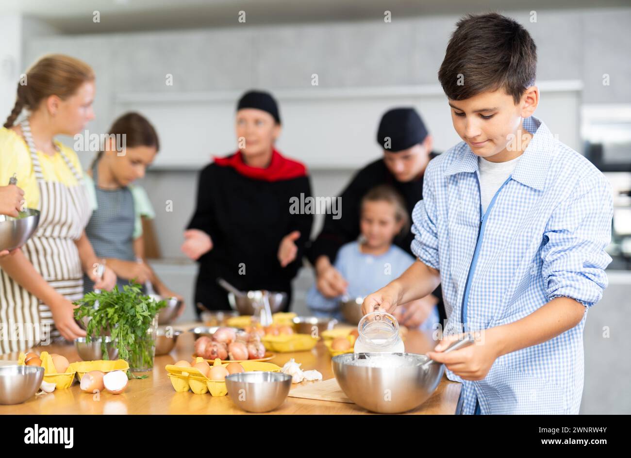 Cooking course - portrait of teenage boy in an apron who is learning to ...