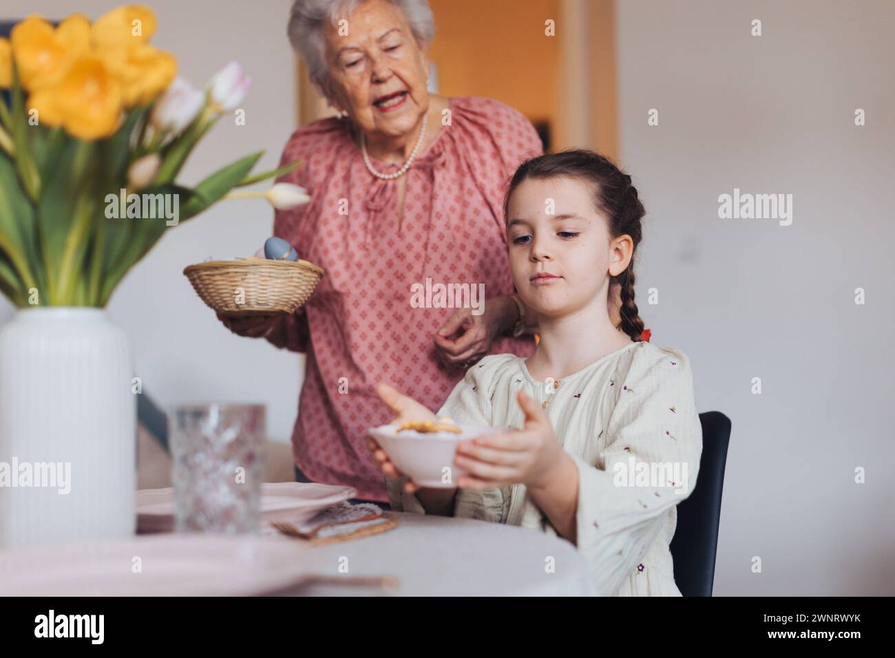 Grandmother with granddaughter setting table for traditional easter ...