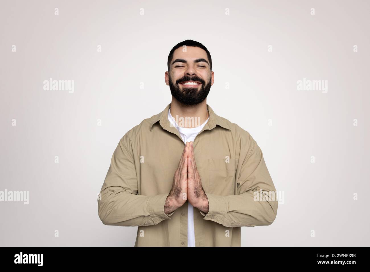 A cheerful man with a neat beard and a bright smile makes a prayer ...