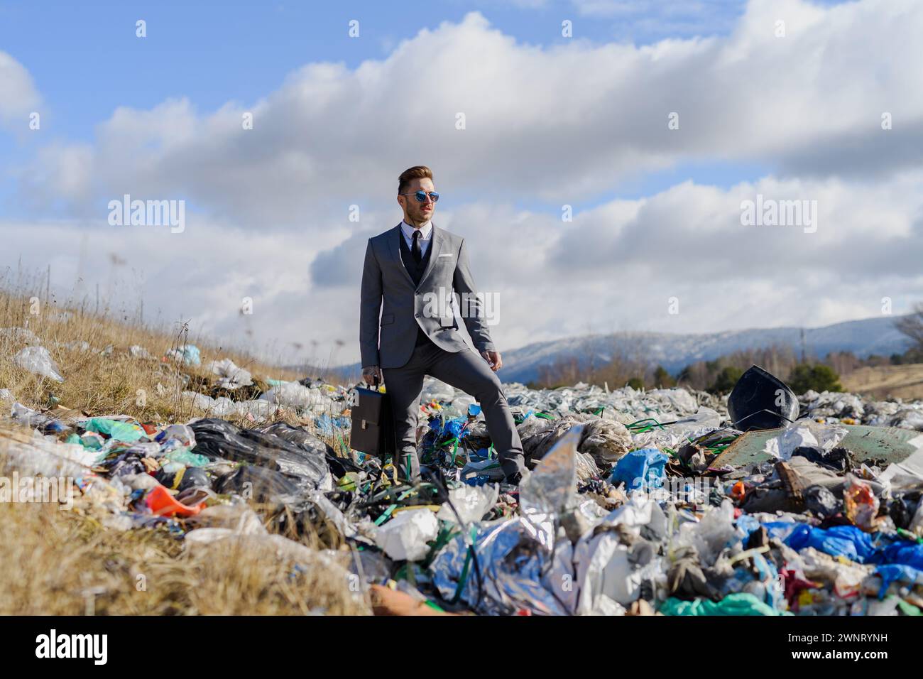 Businessman standing on landfill, large pile of waste. Consumerism ...