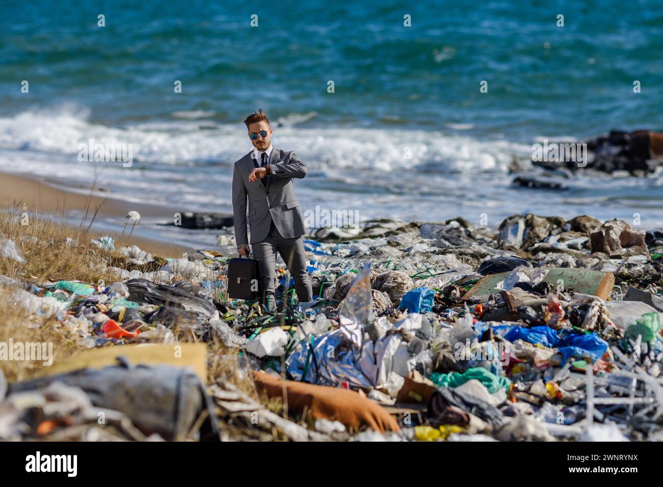 Businessman looking at watch, checking time standing on pile of waste ...
