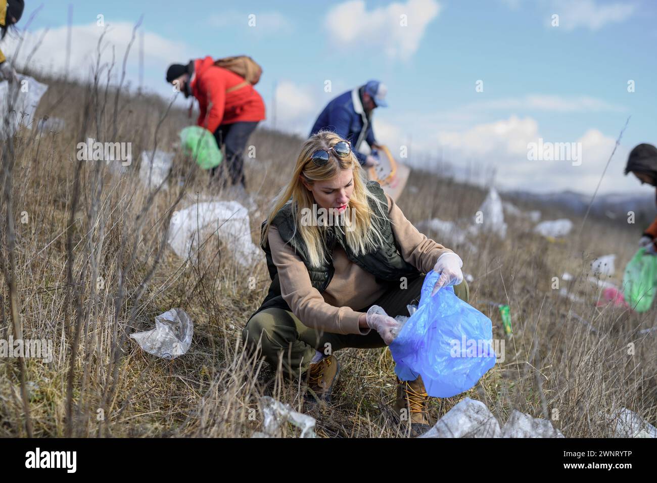 Group of activists picking up litter in nature, environmental pollution ...