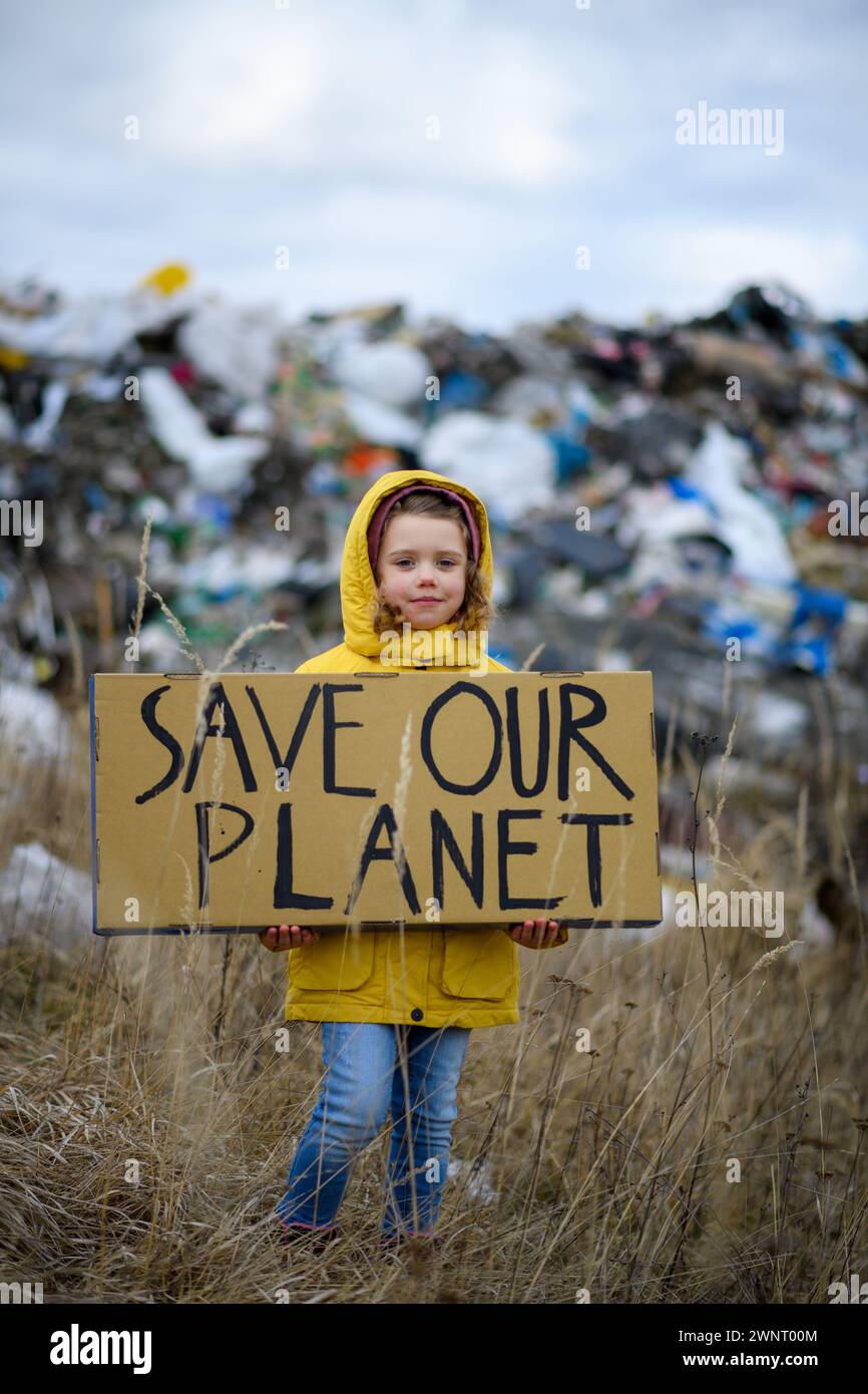 Young girl holding placard, protest sign, standing standing on landfill ...