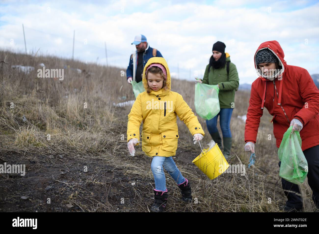 Little girl among eco activists picking up litter in nature ...