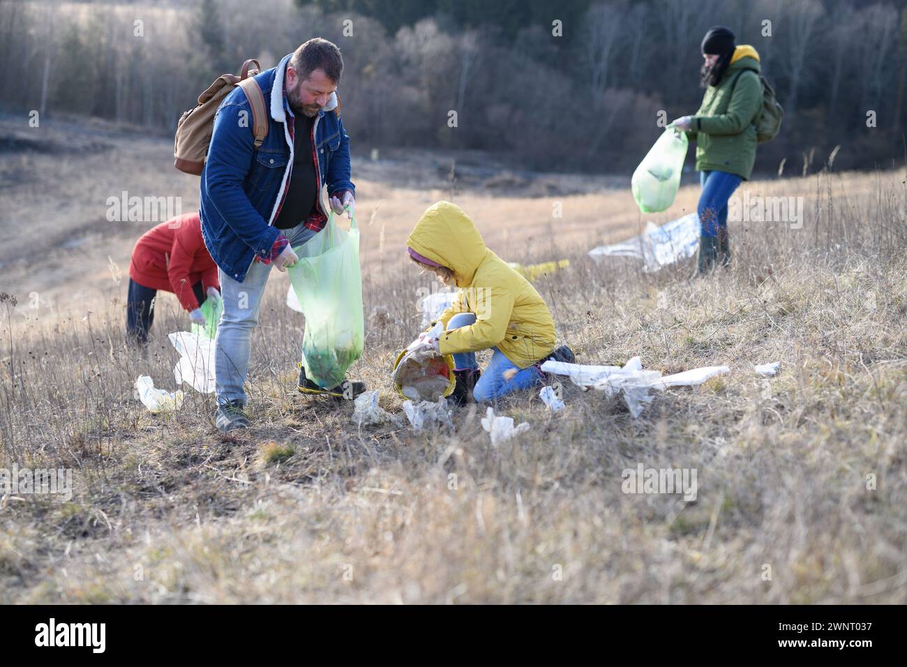 Little girl among eco activists picking up litter in nature ...