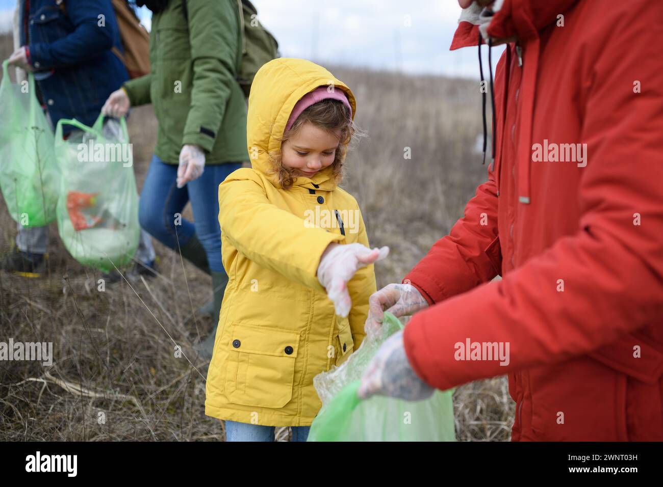 Little girl among eco activists picking up litter in nature ...