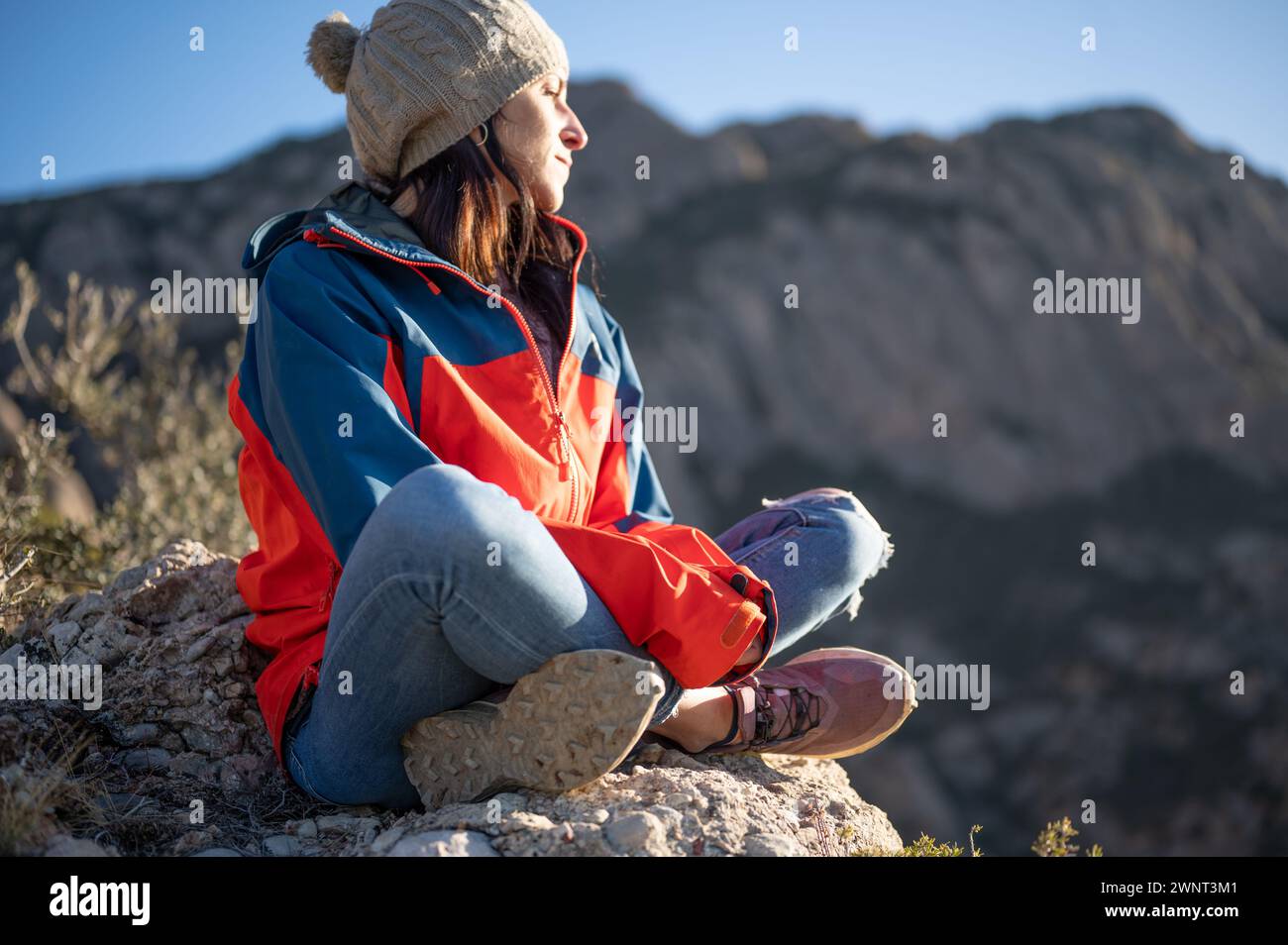Woman sitting on a rock looking out over the landscape Stock Photo - Alamy