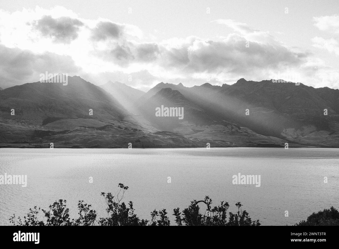 Sun beams shine through clouds onto mountain landscape Stock Photo - Alamy
