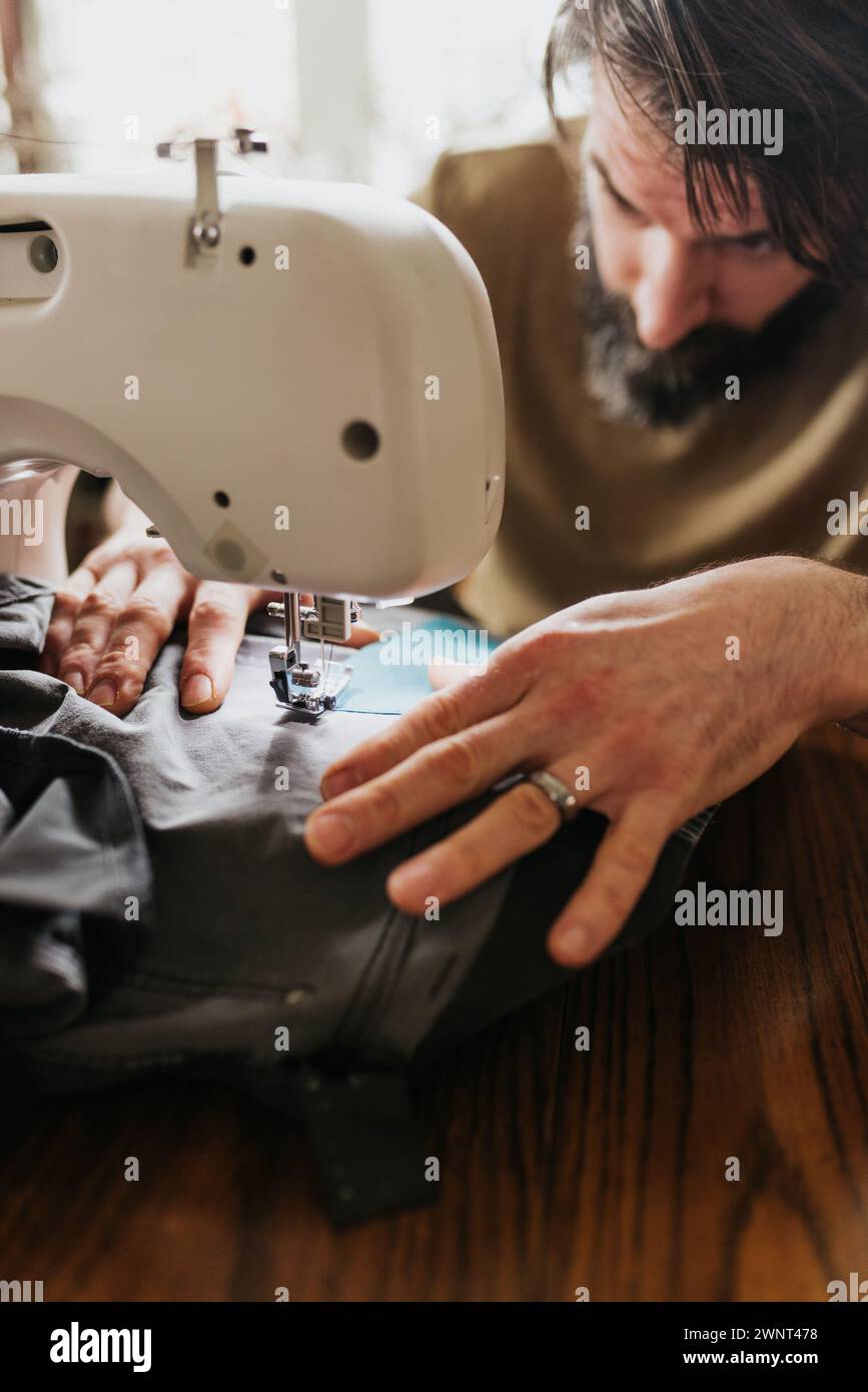 Man sits at kitchen table with sewing machine patching work pants Stock ...
