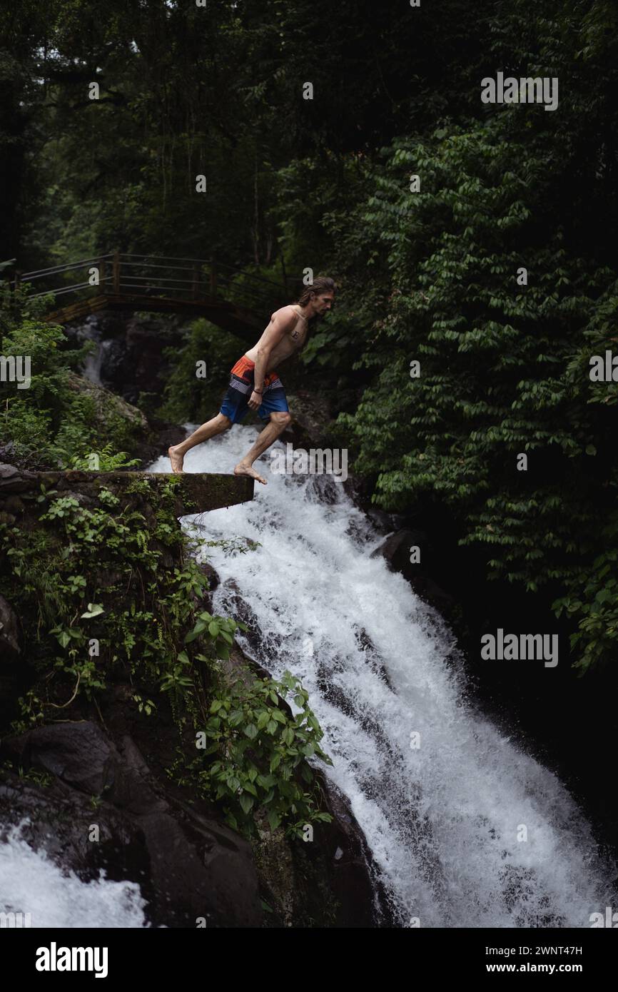 Man jumps from a cliff into the Alin-Alin waterfall. Bali Stock Photo - Alamy