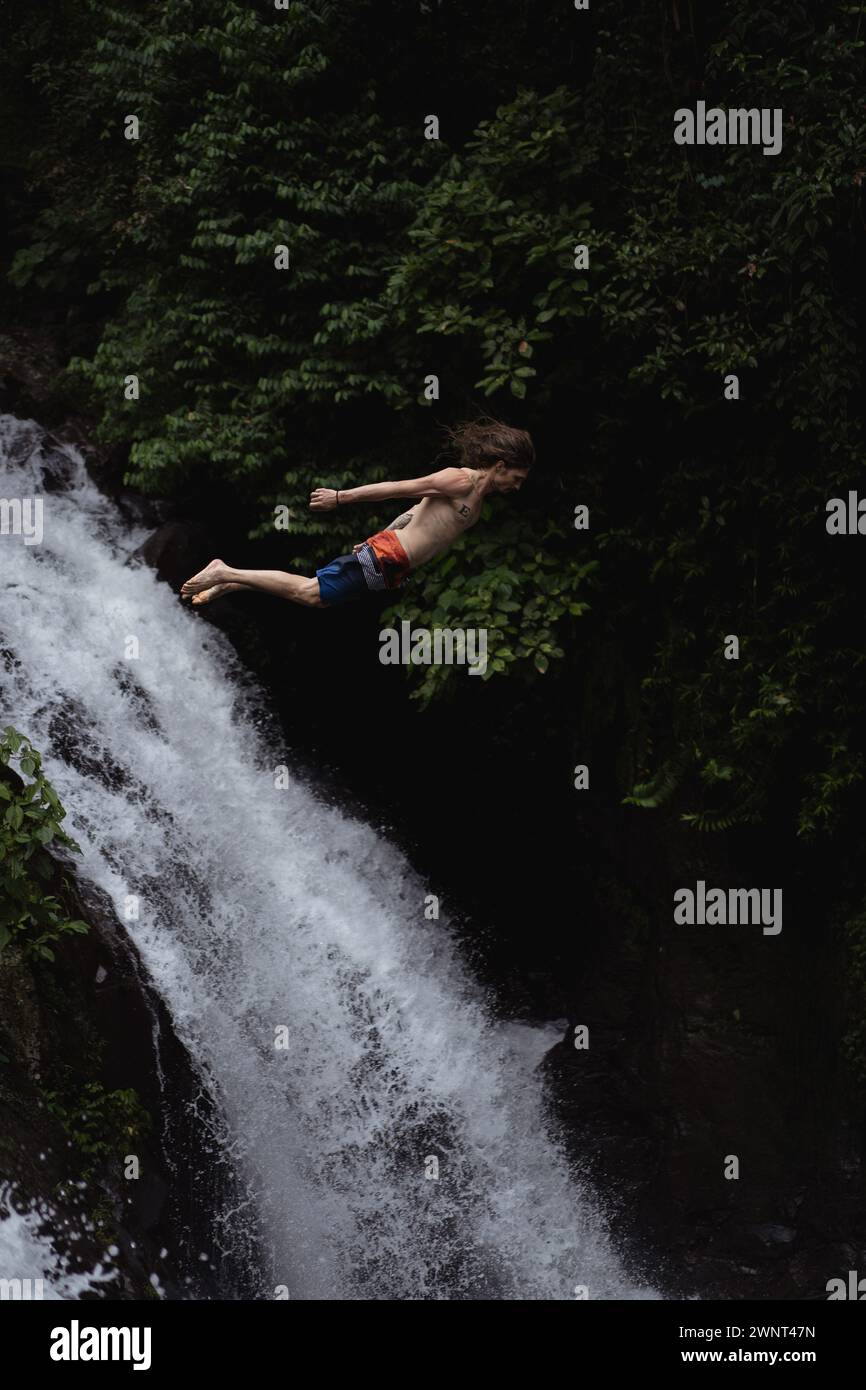 Man jumps from a cliff into the Alin-Alin waterfall. Bali Stock Photo ...