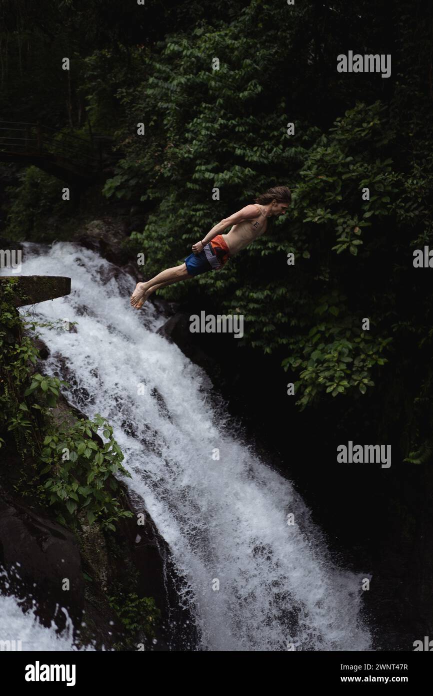 Man jumps from a cliff into the Alin-Alin waterfall. Bali Stock Photo ...