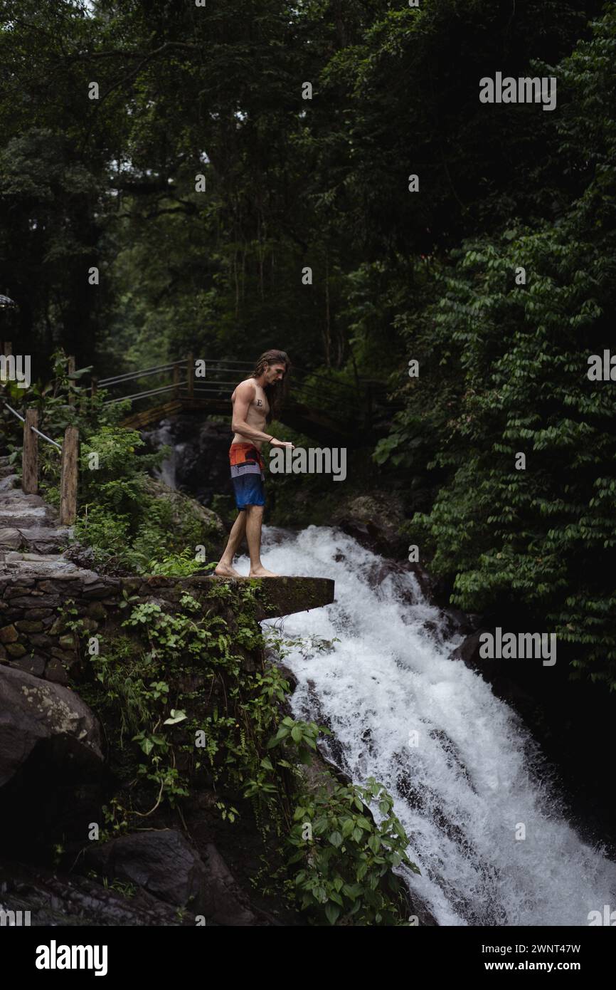 Man is preparing to jump from a cliff into the Aling-Aling waterfall ...