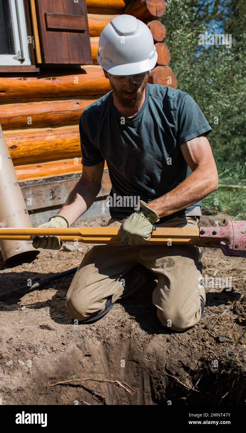 Worker intently digging at construction site Stock Photo - Alamy