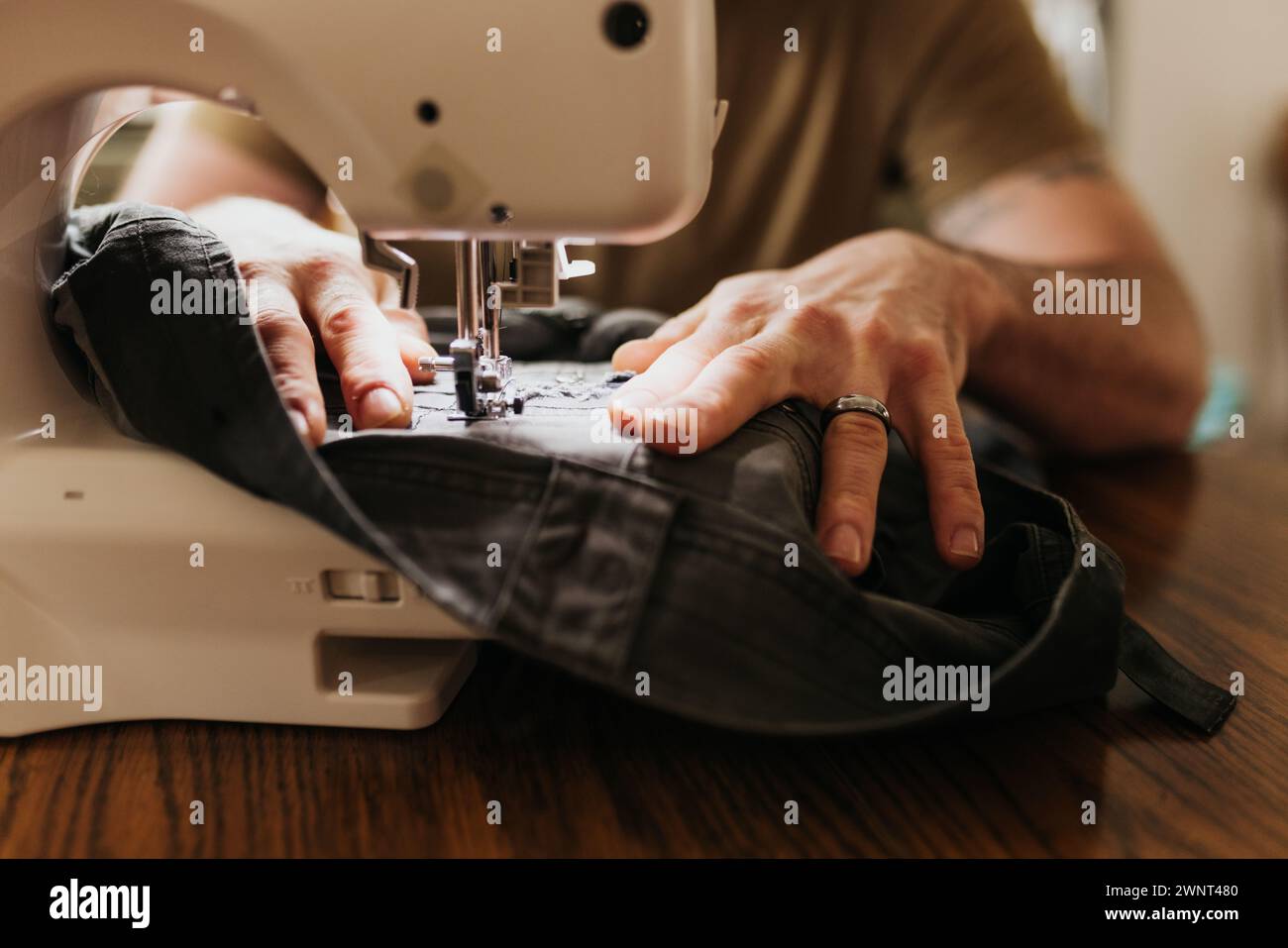 Man sits at kitchen table with sewing machine patching work pants Stock ...