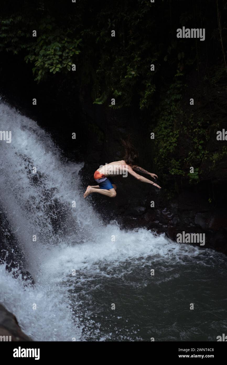 Man jumps from a cliff into the Alin-Alin waterfall. Bali Stock Photo ...