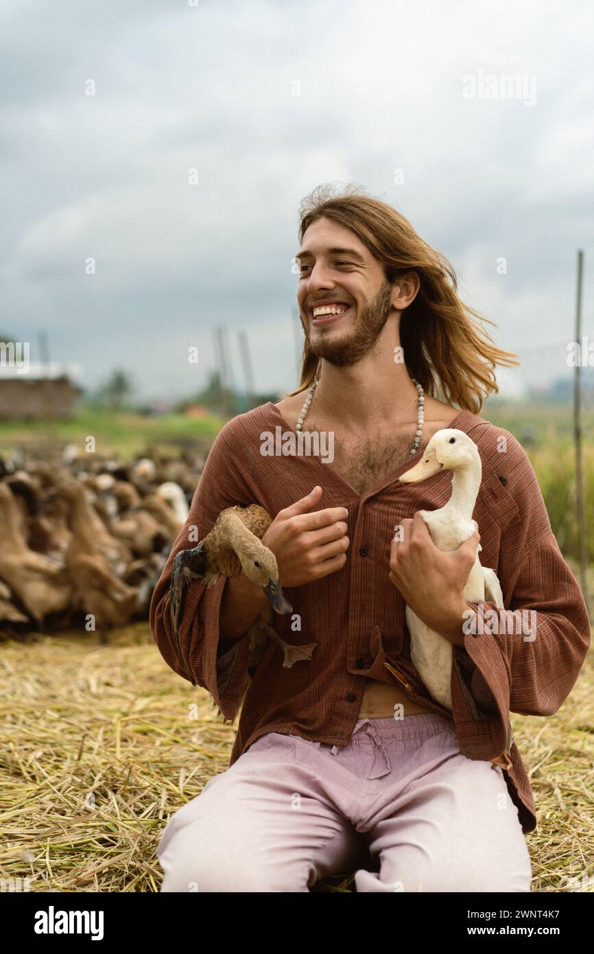 Smiling long-haired man holds ducks in his hands Stock Photo - Alamy