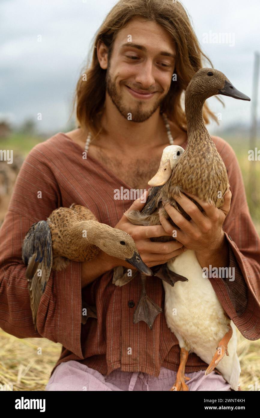 Happy long-haired man holds ducks in his hands Stock Photo - Alamy
