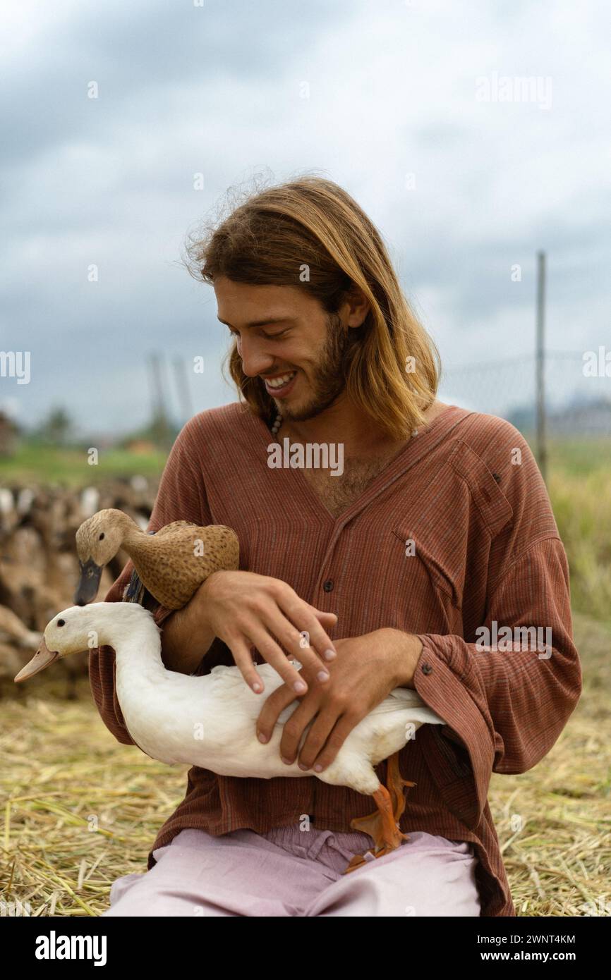 Smiling long-haired man holds ducks in his hands Stock Photo - Alamy