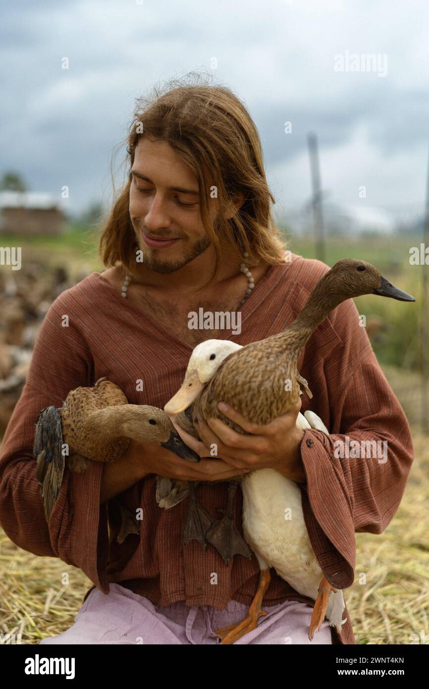 Smiling long-haired man holds ducks in his hands Stock Photo - Alamy