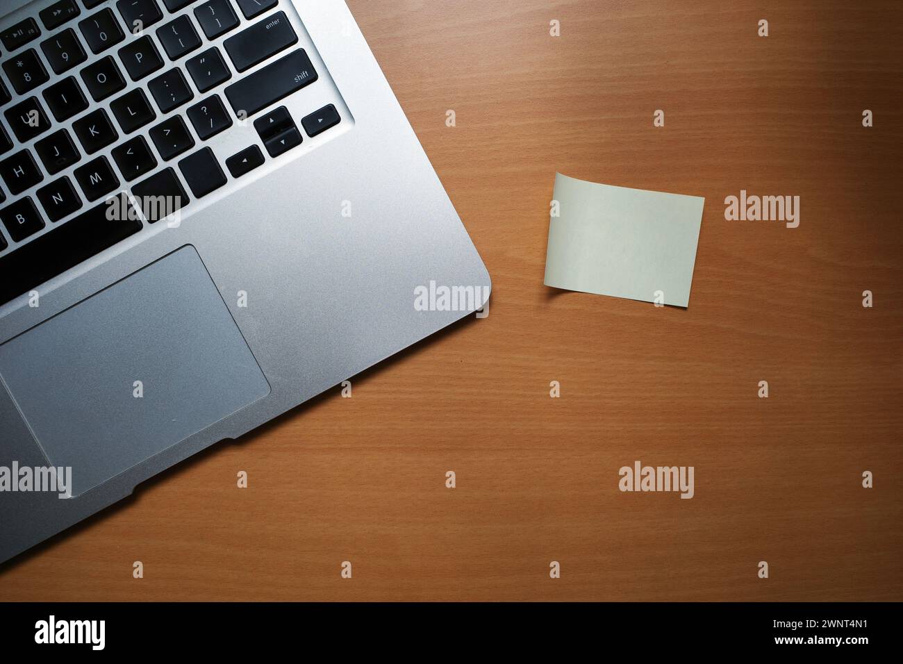 A business desk table with a laptop and a sticky note paper. Wood ...